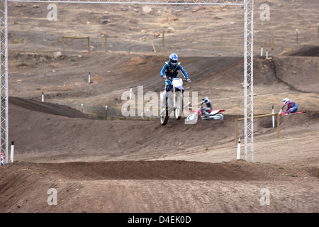 A motorcycle rider jumps through the finish line at an off road ...