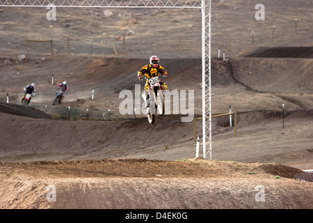 A motorcycle rider jumps through the finish line at an off road ...