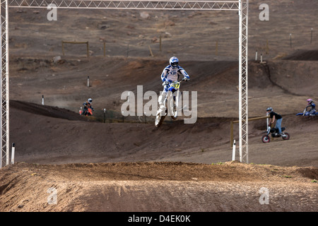 A motorcycle rider jumps through the finish line at an off road ...