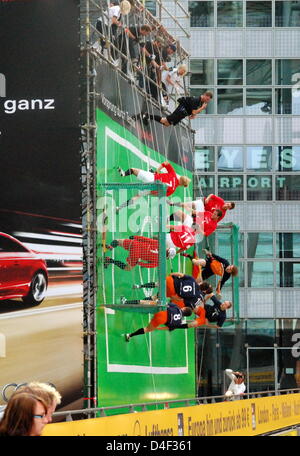 Football players hanging on ropes, playing football on a vertical field ...
