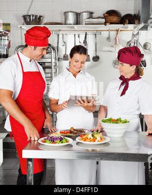 Chefs using computer in restaurant kitchen Stock Photo - Alamy