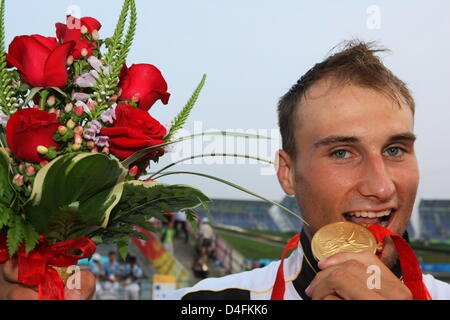 German Alexander Grimm bites his goldmedal on the podium after winning ...