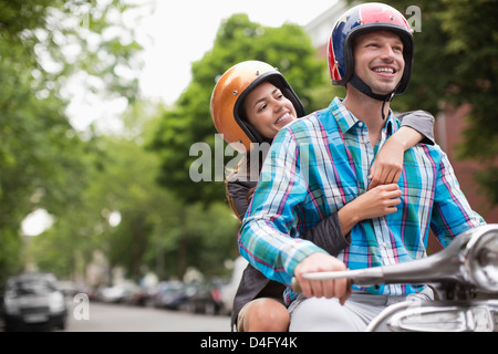 Cheerful young couple riding a scooter and having fun Stock Photo - Alamy