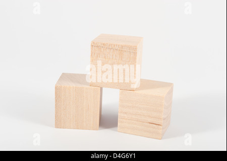 Three wooden building blocks stacked together on a bright yellow ...