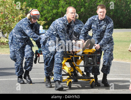 US Navy Sailors transport injured personnel to a medical station during ...