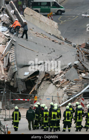 A group of firefighters in uniform stand with a ladder truck in the ...