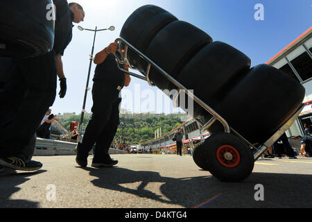 A mechanic pushes a trolley with tyres through the paddock at the ...