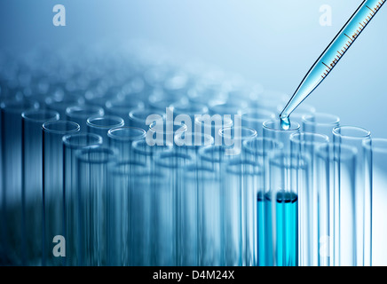 Laboratory pipette with drop of color liquid over glass test tubes ...