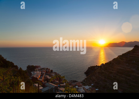 Sun setting over a hill with a beam of light stretching across an ...
