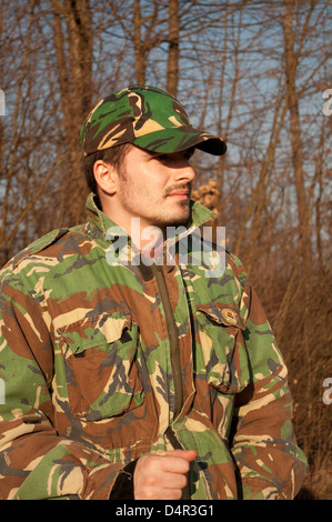 Soldier man in camouflage jacket clapping hands in a pink studio with ...