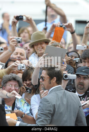 Brad Pitt signs autographs as he arrives for the premiere of the film ...