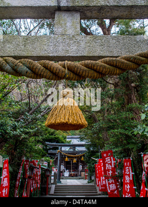 A sacred rice straw rope (shimenawa) marks the entrance to a Shinto ...