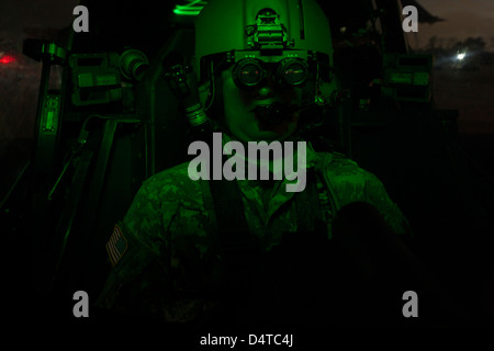 A pilot equipped with night vision goggles in the cockpit of an AH-64 ...