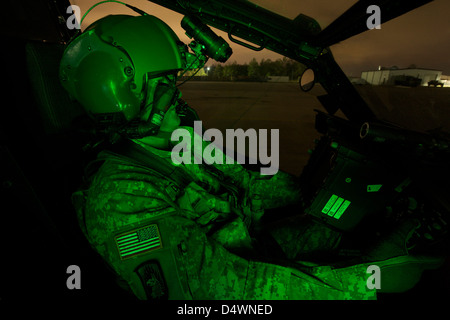 A pilot equipped with night vision goggles in the cockpit of an AH-64 ...