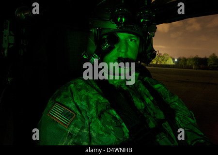 A pilot equipped with night vision goggles in the cockpit of an AH-64 ...
