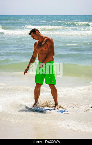 Male college student surfing along the waterfront on Siesta Key beach ...