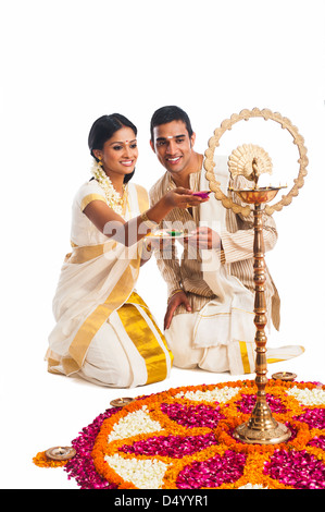 Women Lighting lamp and traditional flower bed for Onam, harvest ...