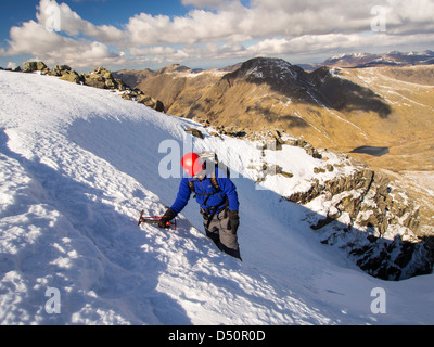 A climber topping out in Custs Gully on Great End, a grade one winter ...