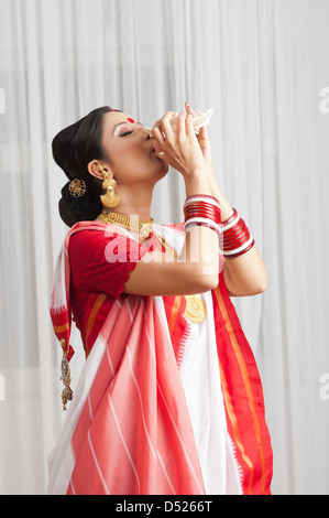 Woman in a Bengali sari blowing conch shell Stock Photo - Alamy