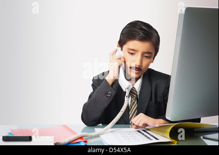 Boy imitating like businessman talking on a mobile phone while working ...
