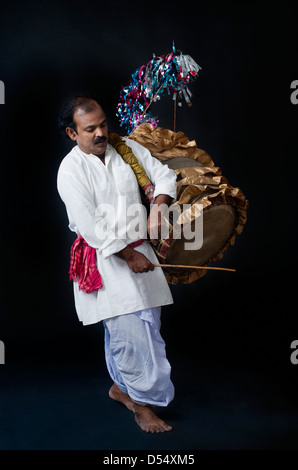 Bengali man playing dhol (A large drum used to play during festival and ...