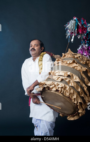 Bengali man playing dhol (A large drum used to play during festival and ...