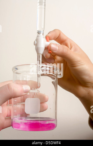 A pipette drips ordinary vinegar (acid) into a beaker containing a ...