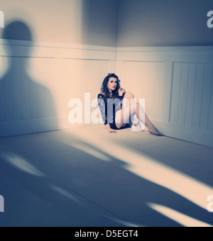 Sad woman sitting alone in a empty room Stock Photo - Alamy