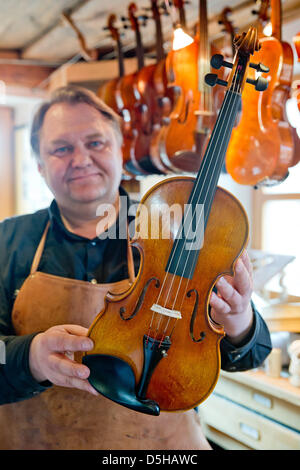 Violin maker Walther Mahr holds two violins made from spruce wood, one ...