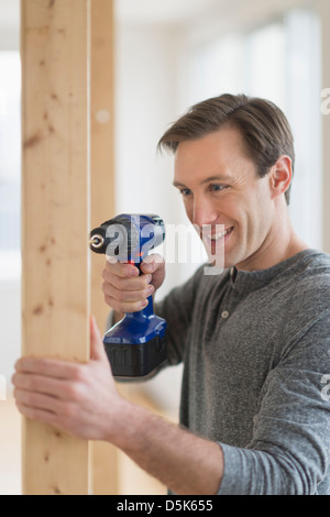 happy construction man using a drill to secure a beam Stock Photo - Alamy