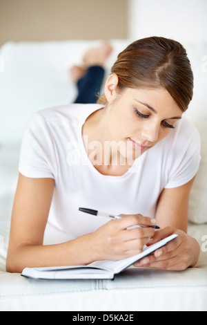 A woman lying on bed and writing in a diary with her companion shiba ...