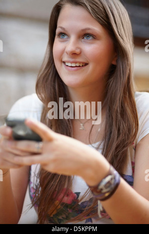 Smiling woman using mobile phone against building Stock Photo - Alamy