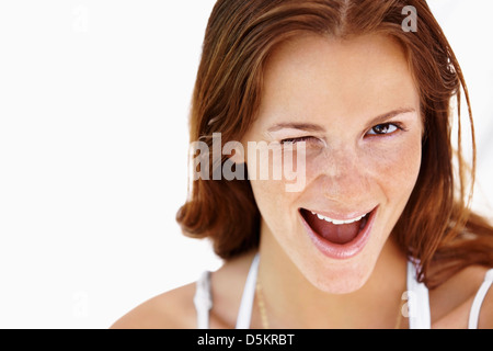 Portrait of playful young woman winking against colored background ...
