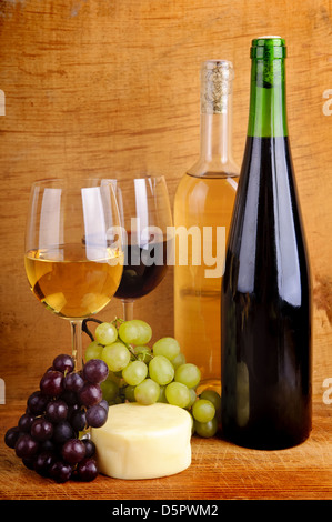 Glasses with red and white wine and cheese on a plate on a light ...