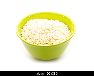 Organic Arborio rice in a white bowl on a black surface, top view. Flat ...