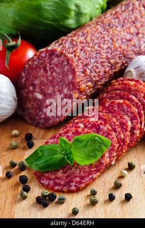 Salami sausage slices and leaf green basil isolated on white background. Few pieces or several ...