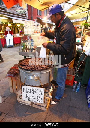 A male chestnut seller on the street at night with a small wagon for ...