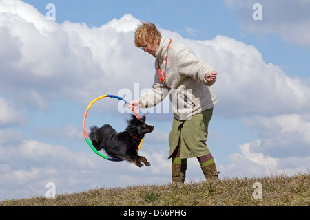 Woman training her dog jumping through tire at park Stock Photo - Alamy
