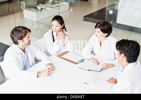 Group of doctors sitting at meeting table in conference room during ...