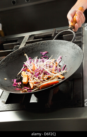 Chef cooking vegetables in wok pan Stock Photo - Alamy