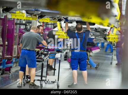 Several employees of car manufacturer BMW work on a car at the BMW ...