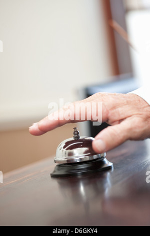 Man ringing in service bell on reception desk Stock Photo - Alamy