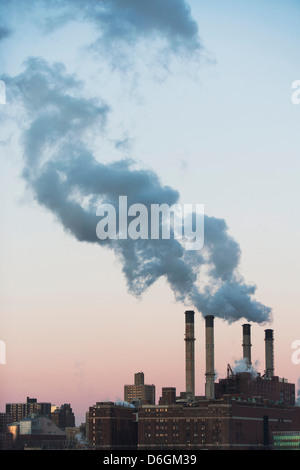 Smoke billowing from an industrial building at sunrise creates a ...
