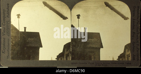 This stereoview shows a Zeppelin airship flying over a German town ...