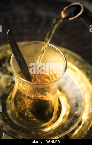 Pouring of Turkish tea into glass on white background Stock Photo - Alamy