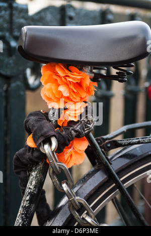 Orange dutch bicycle bike chained to bridge railings over a canal in ...