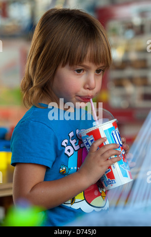 Little cute thirsty girls drinks water from a drinking sink on the ...