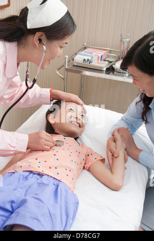 Doctor listening to little girl's heart with stethoscope, side view ...