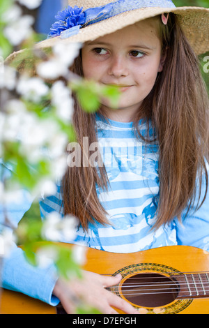 cheerful girl in straw hat looking at camera in hands of mom outdoors ...