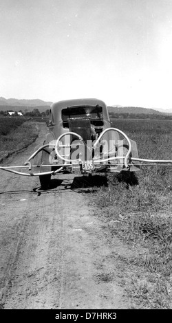 Crop spraying equipment mounted on wide tractor travelling along narrow ...